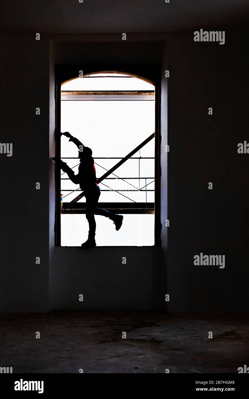 Worker balancing on a window while working. Building site Stock Photo ...