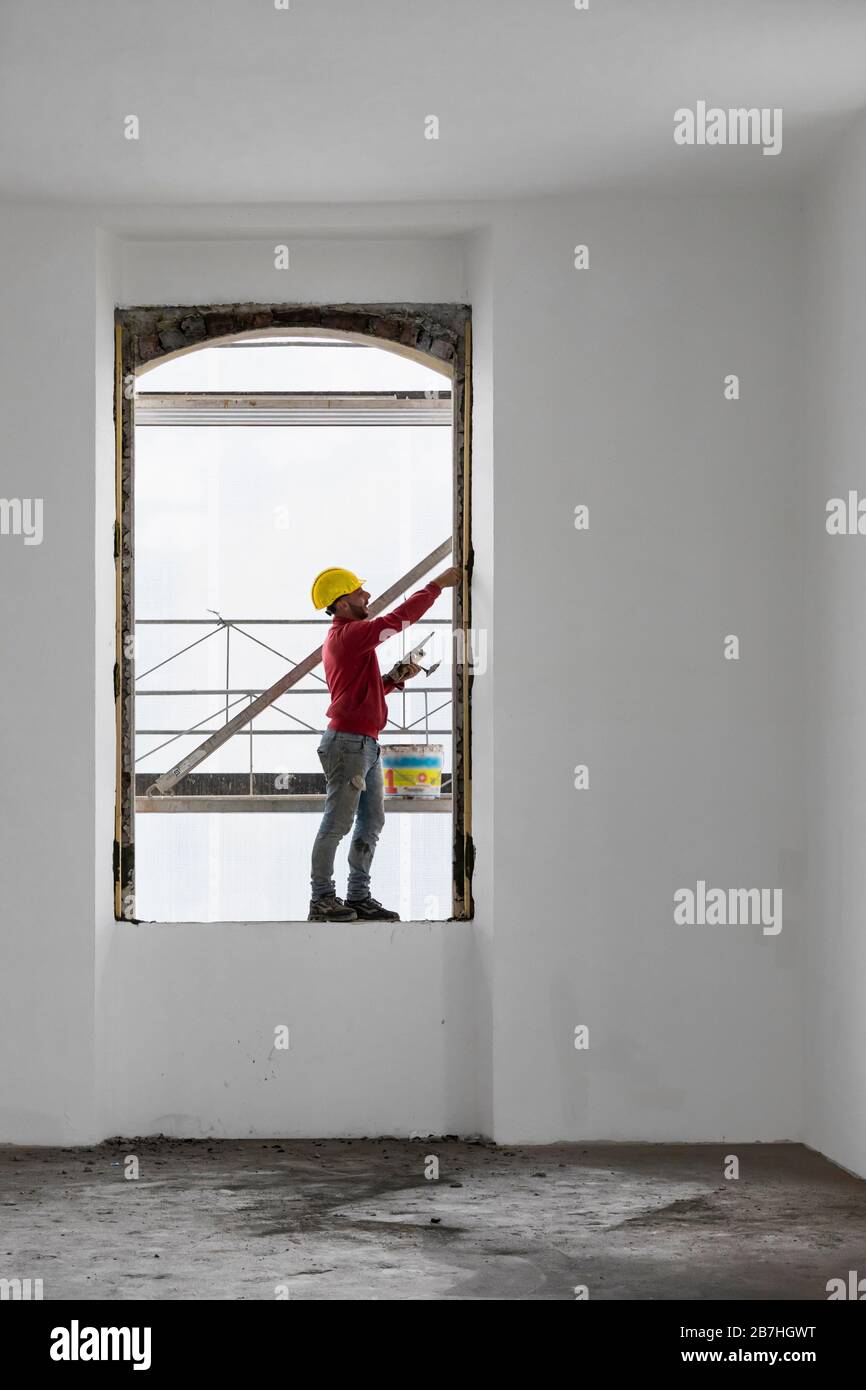 Worker balancing on a window while working. Building site Stock Photo ...