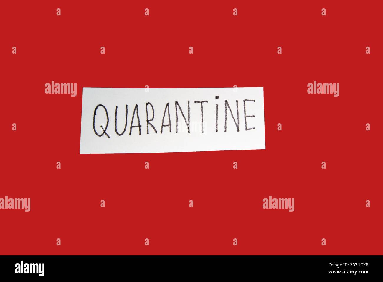 The word quarantine written on a piece of paper, isolated on a red ...