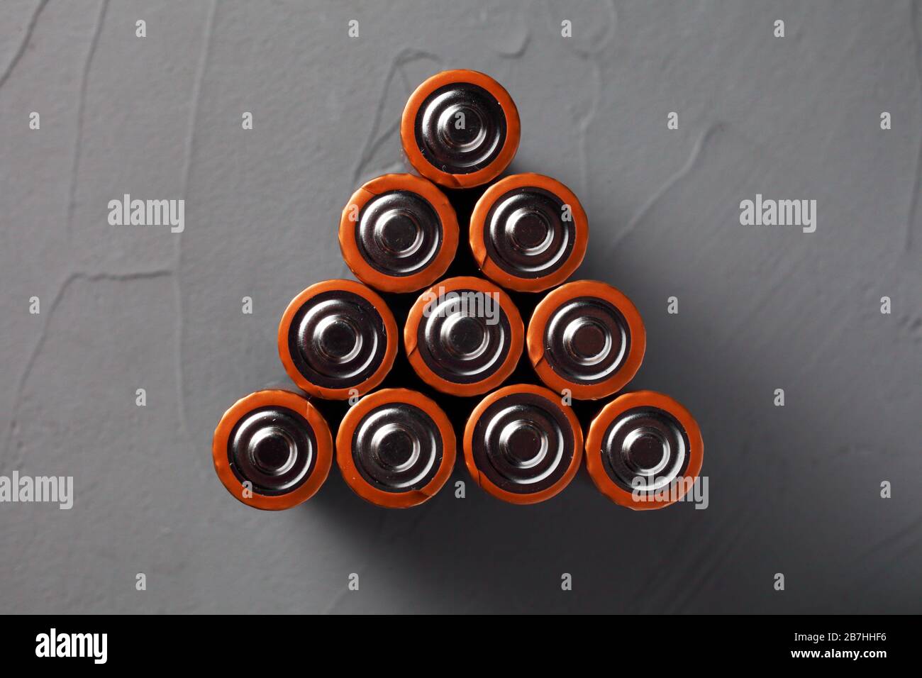 AA batteries lined up in the shape of a triangle on a concrete ...