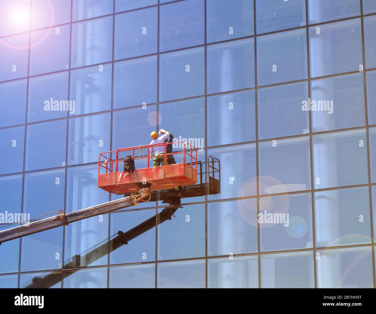 Working window cleaner on a telescopic platform washes the Windows of a ...