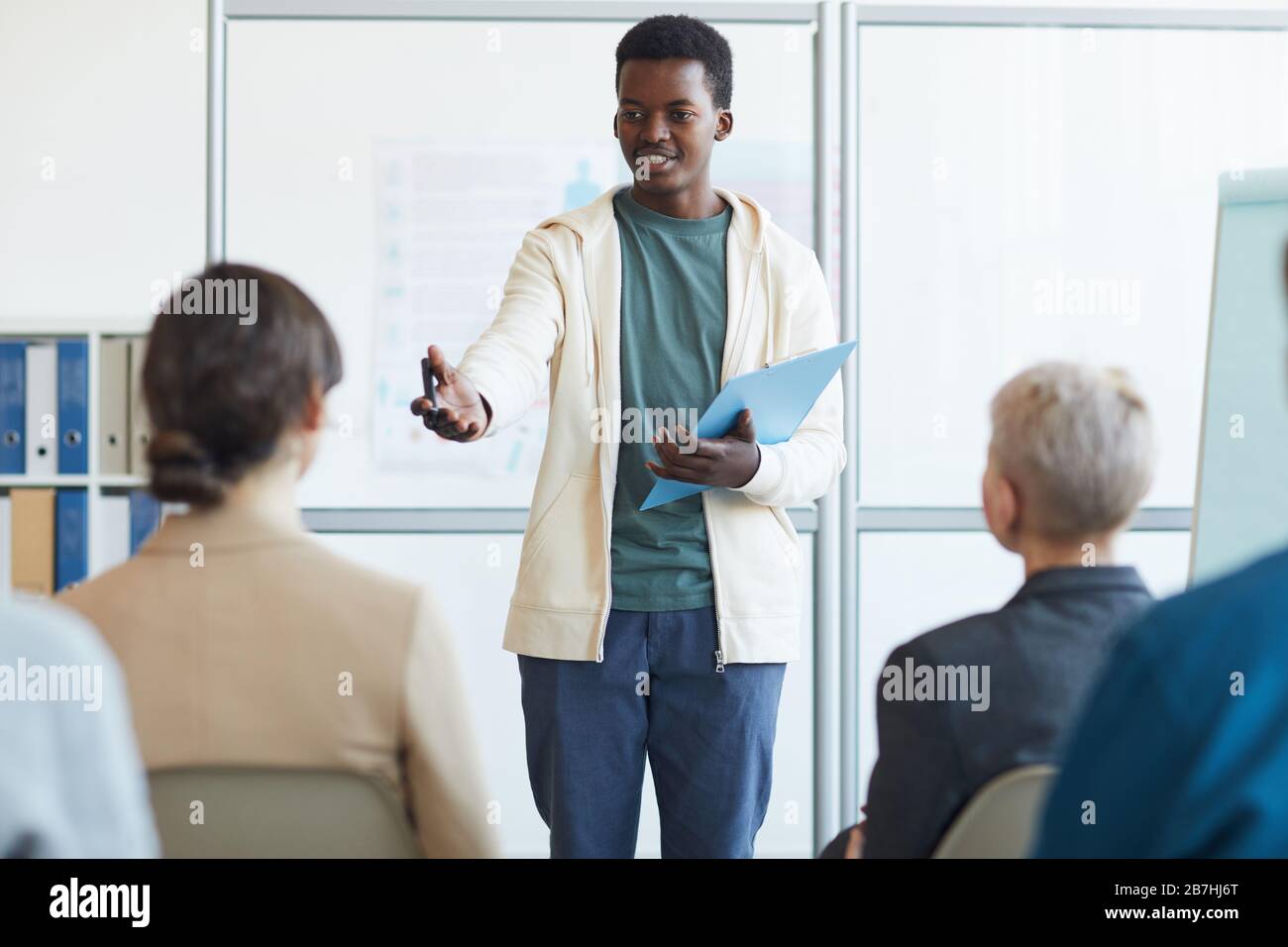 Portrait of young African-American man giving speech during meeting ...