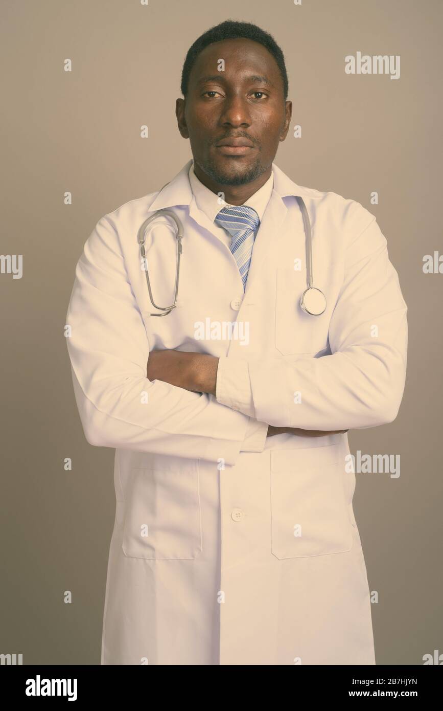 Studio shot of young handsome African man doctor against gray ...