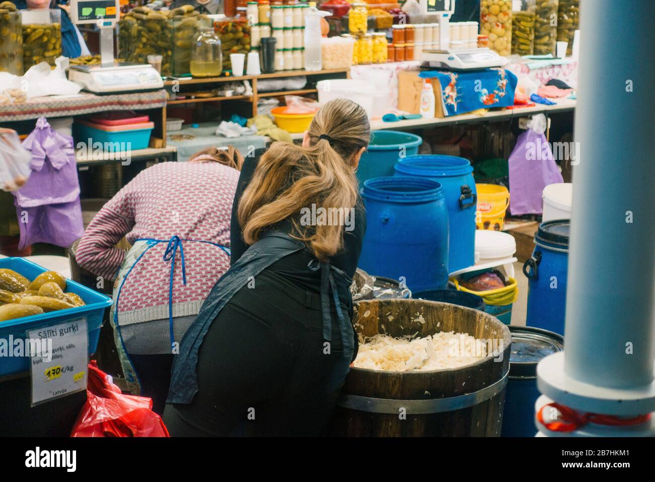 A woman scoops raw shredded cabbage out of a wooden barrel in the Riga ...
