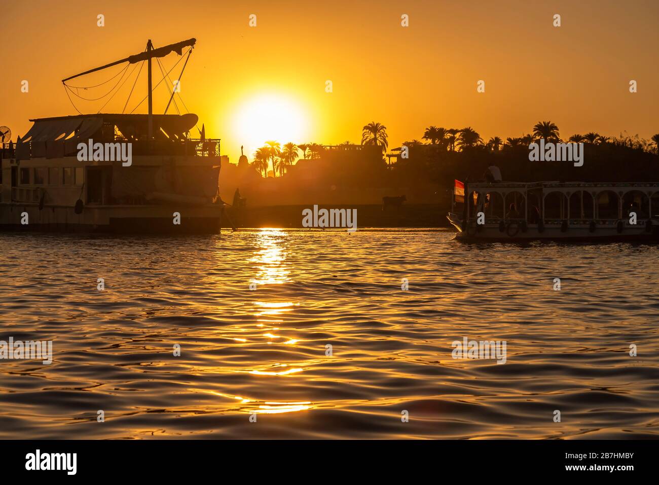 Sun setting over the Nile River in Luxor with silhouettes of ferry ...