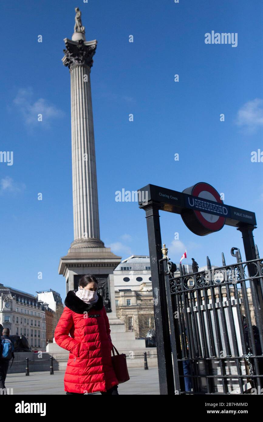 A woman wearing a mask walks through Trafalgar Square, London, as ...