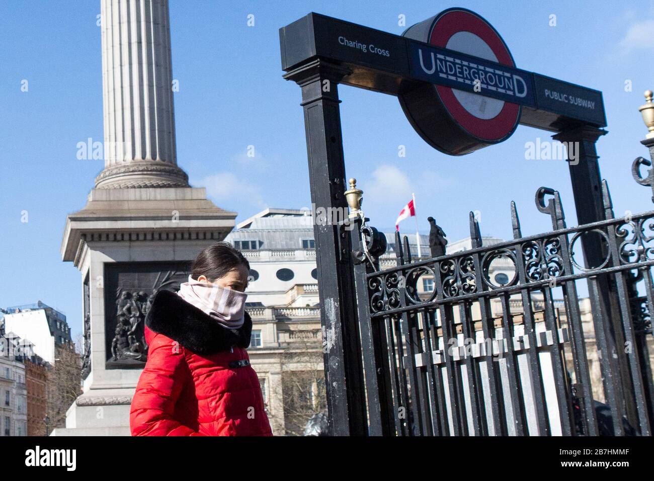 A woman wearing a mask walks through Trafalgar Square, London, as ...