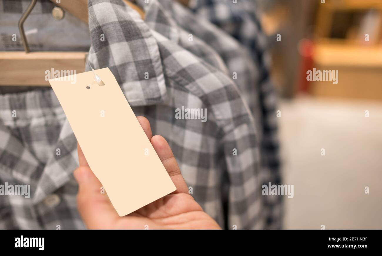 Hand holding blank paper price tag of checked pattern cotton shirt on ...