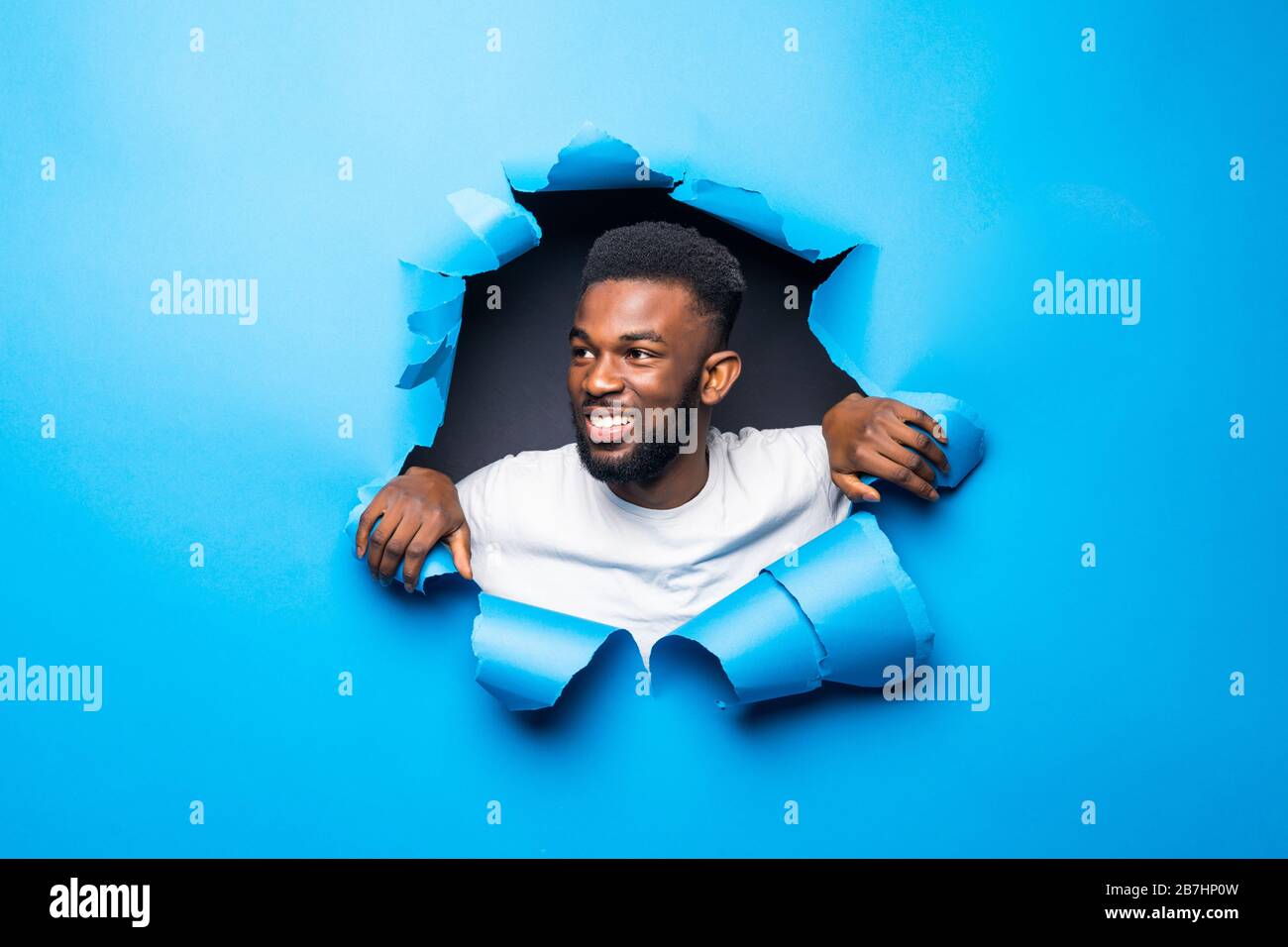 handsome young black man with head through a cardboard paper smiling ...