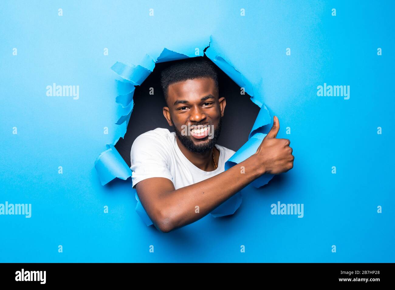 handsome young black man with head through a cardboard paper smiling ...