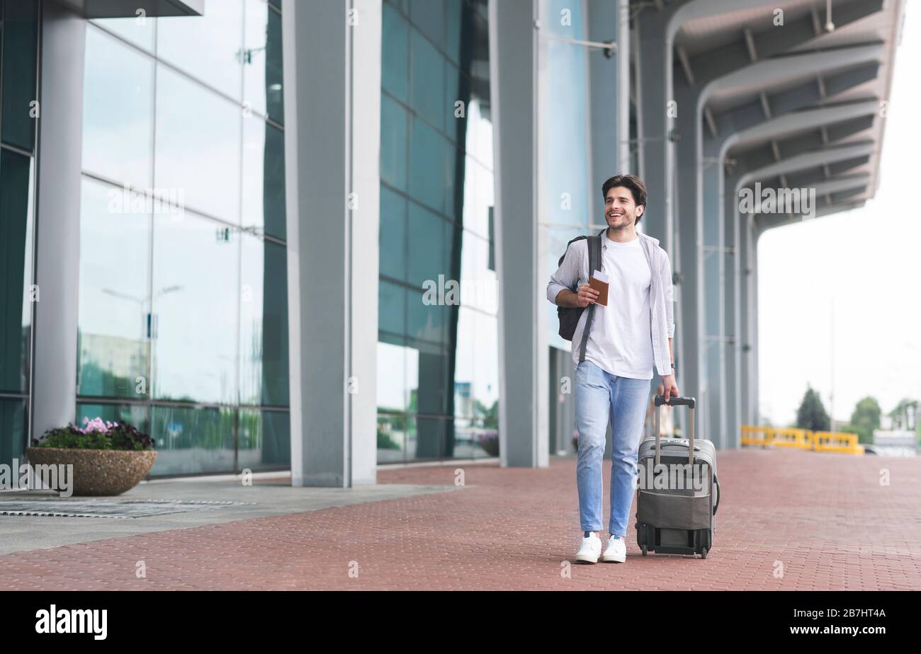 Happy Young Man Walking With Suitcase And Backpack Near Airport ...