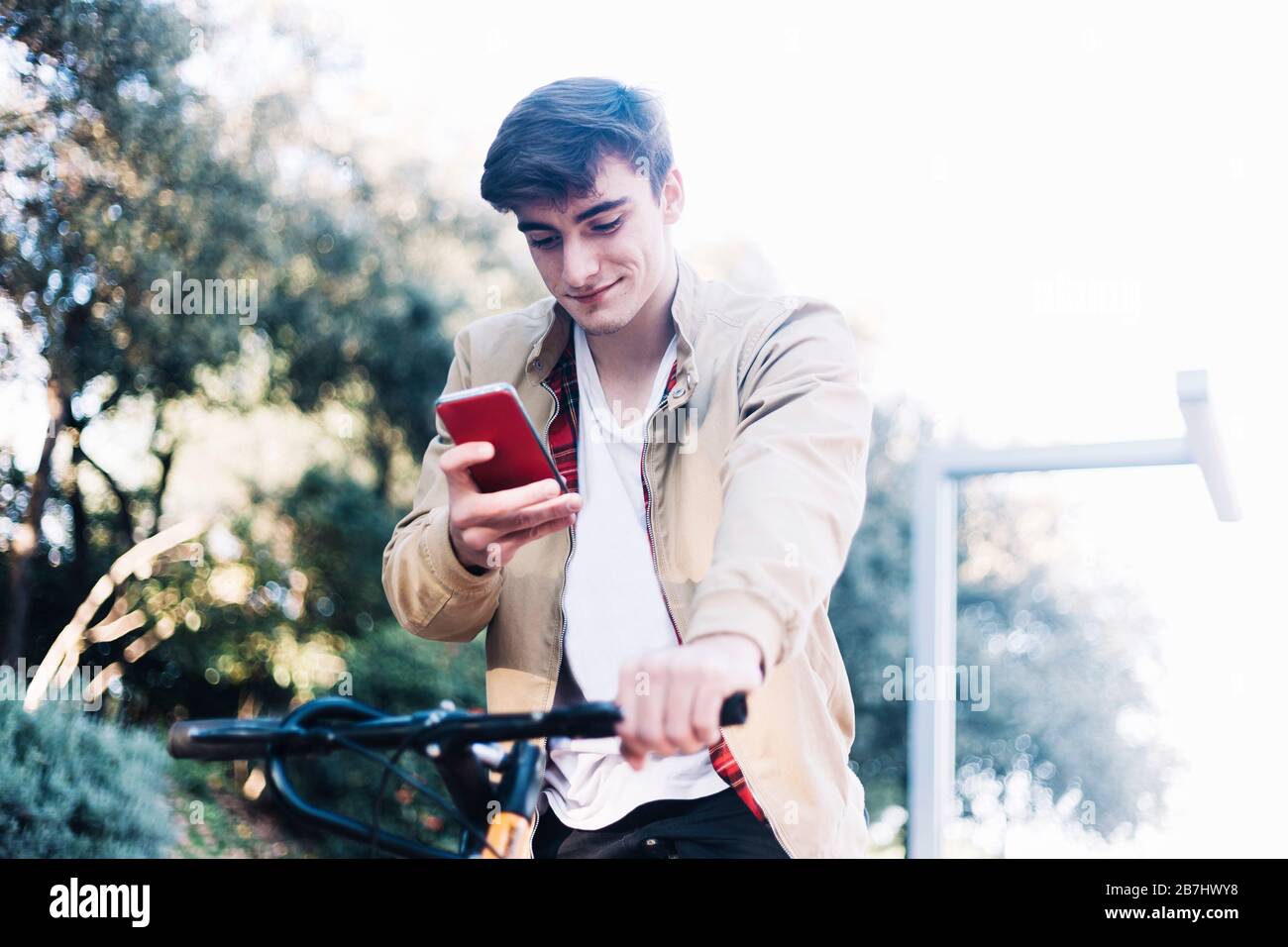 Young guy on a bicycle looking at mobile phone Stock Photo - Alamy
