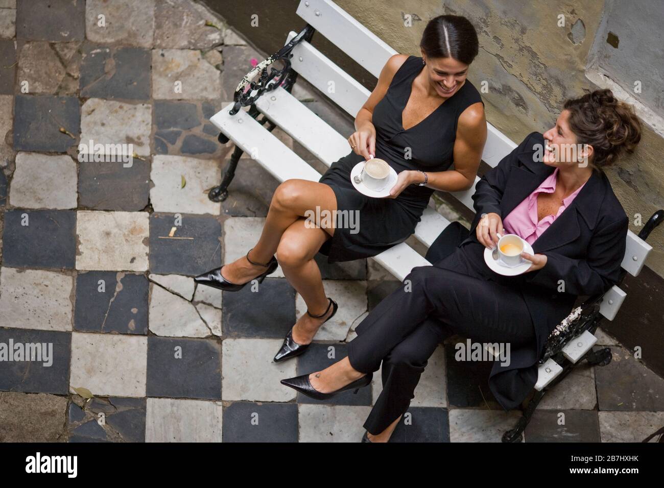 Two smiling mid-adult business woman sitting drinking coffee in a ...