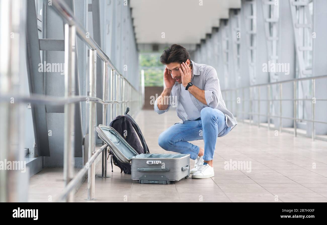 Mixed Up Luggage. Desperate man sitting near airport terminal with ...