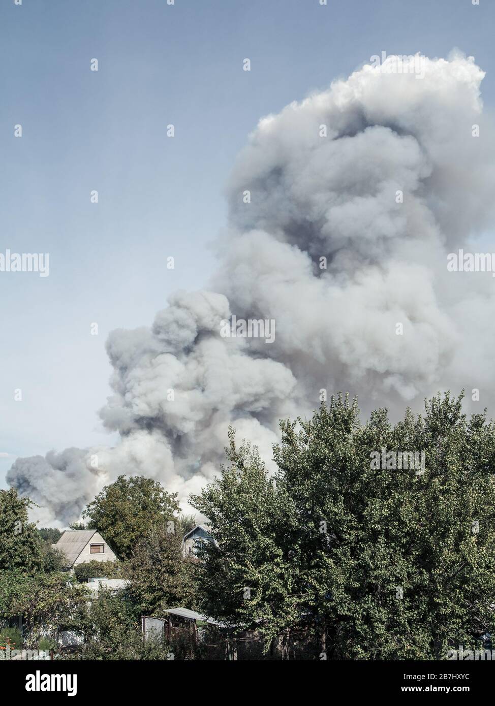 Clouds of gray smoke rising from the raging wildfire with houses and ...