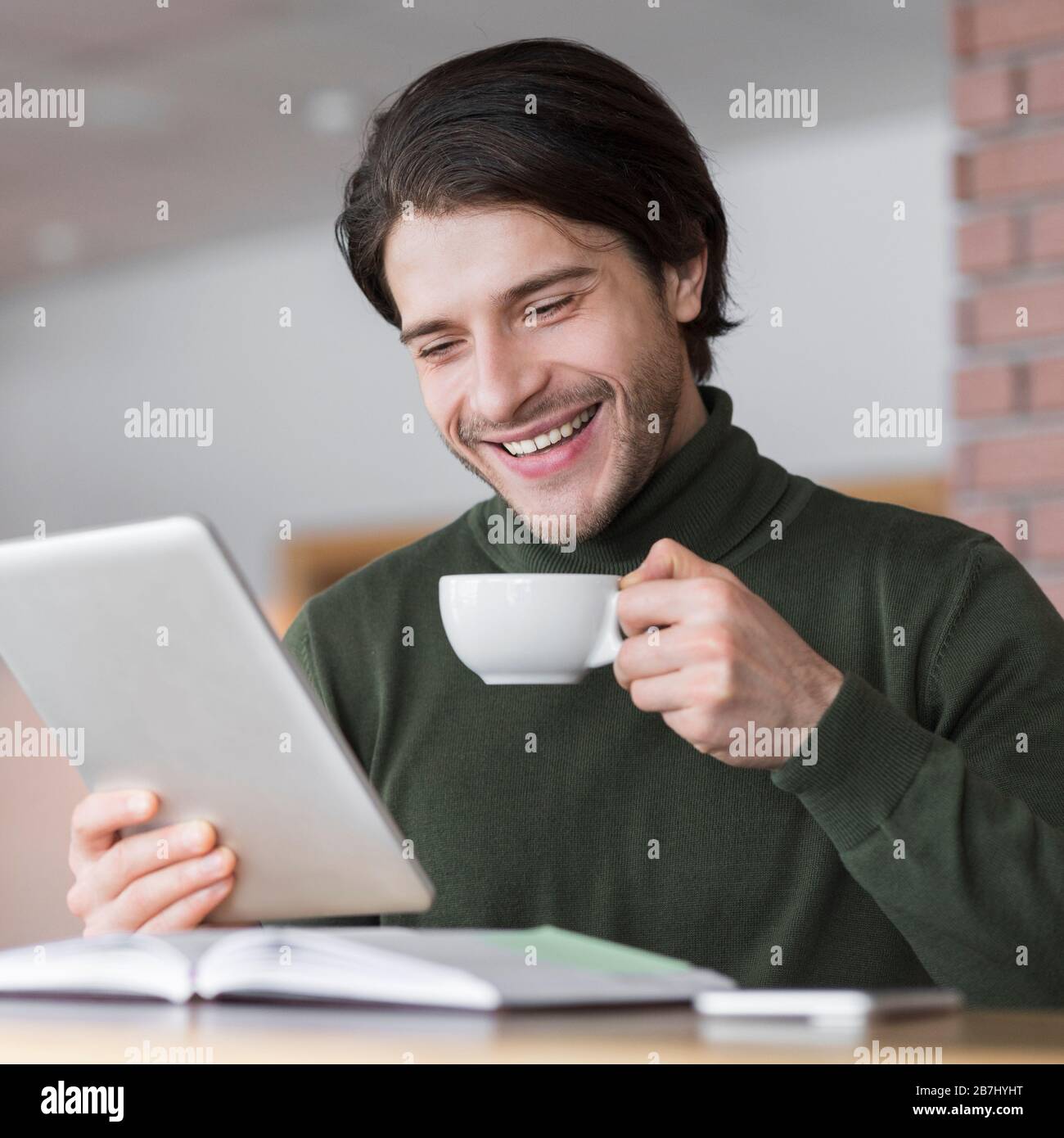 Young successful businessman checking emails while having morning ...