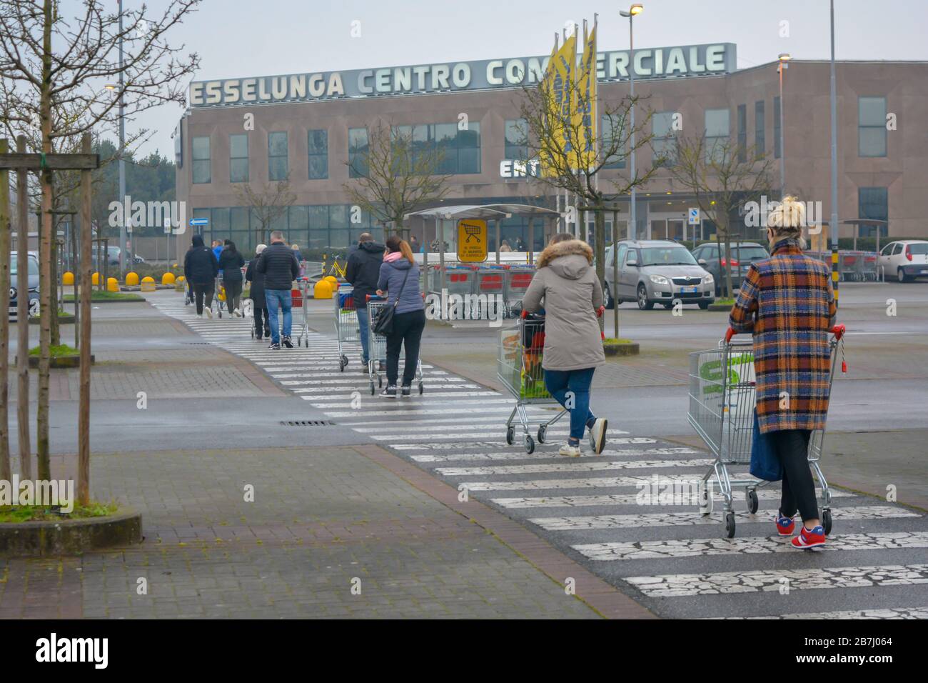 Line of people with shopping carts in grocery store parking lot. People ...