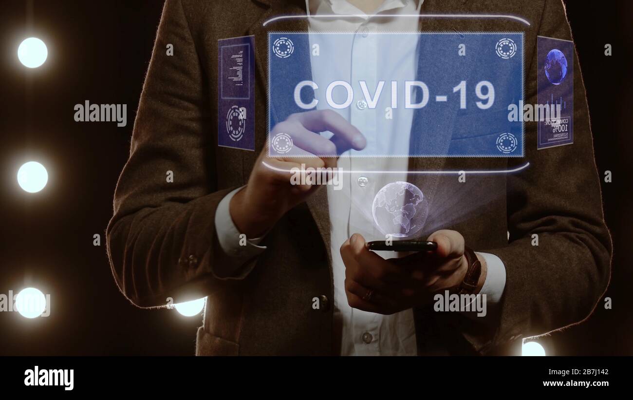 Businessman shows HUD hologram with text COVID-19 Stock Photo - Alamy