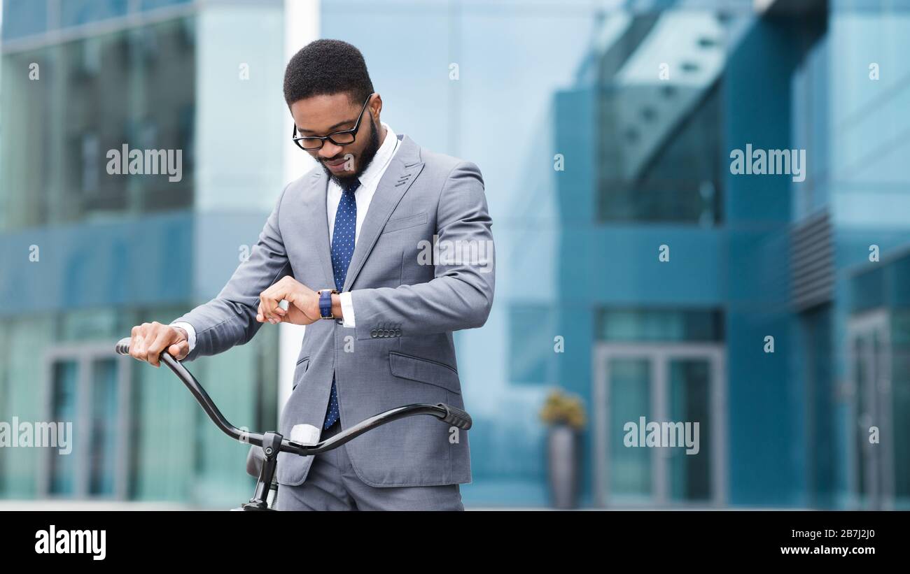 Handsome black manager checking time on wristwatch Stock Photo - Alamy