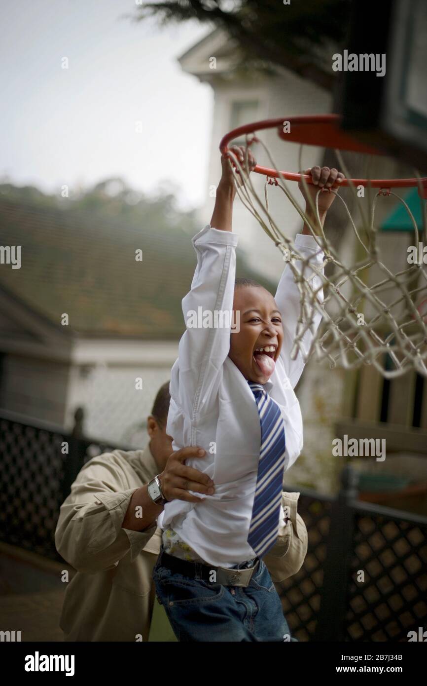 Laughing boy hanging from a basketball hoop Stock Photo - Alamy