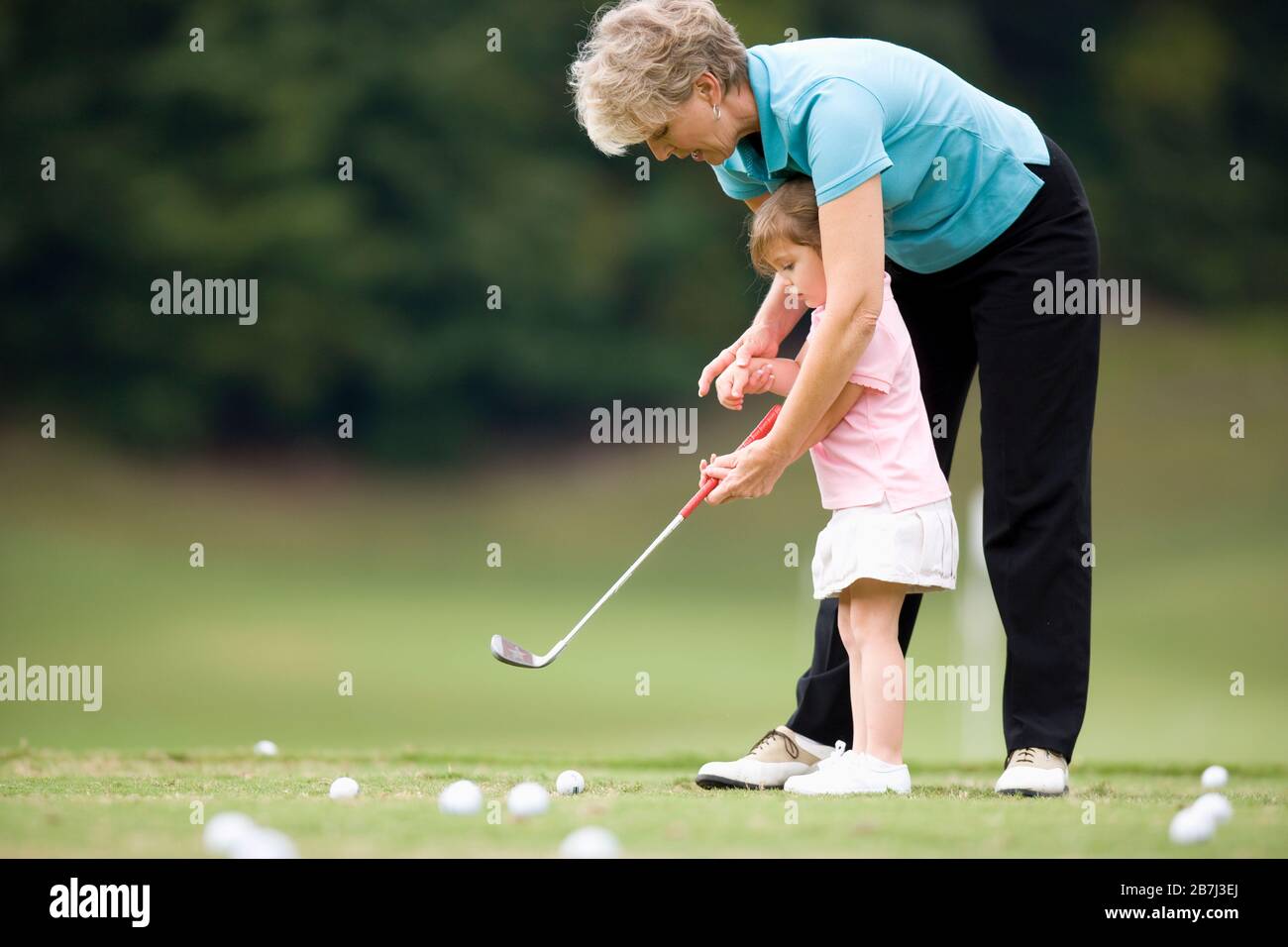 Grandmother teaching her granddaughter to play golf Stock Photo - Alamy