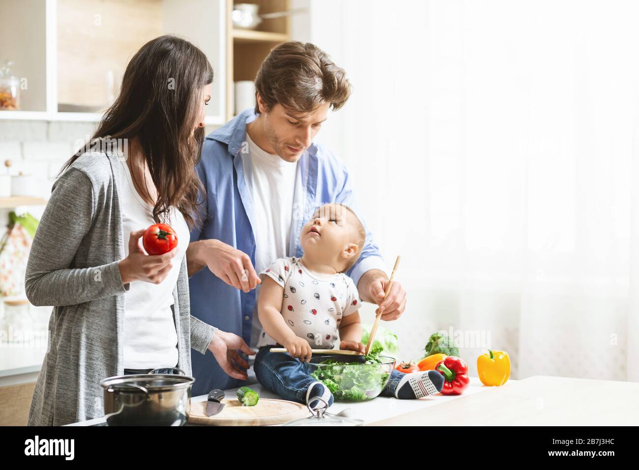 Happy parents teaching baby son to prepare vegetable salad Stock Photo ...