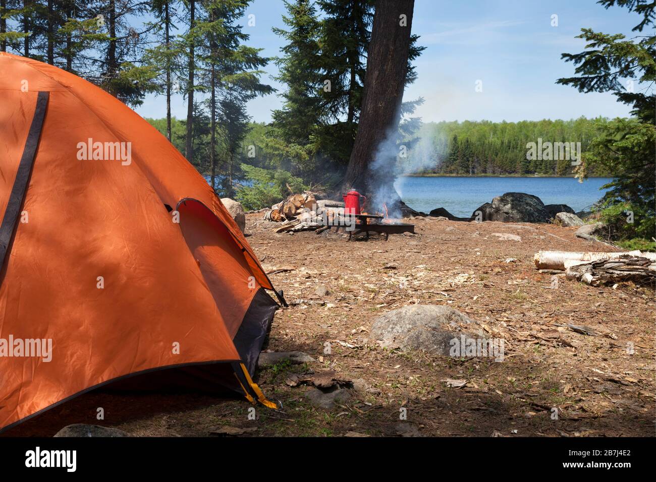 Campsite with orange tent and campfire on a northern Minnesota lake ...