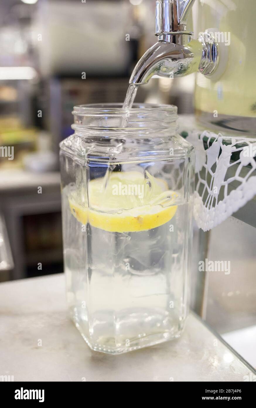 Lemonade dispenser filling a big jar with slice of lemon. Coffee shop ...