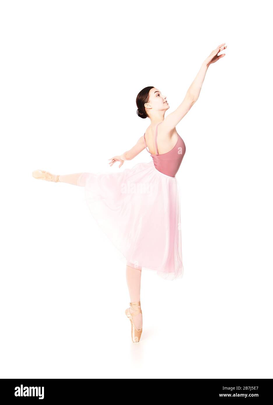 Elegant woman in a pink skirt and beige top dancing ballet. Studio ...