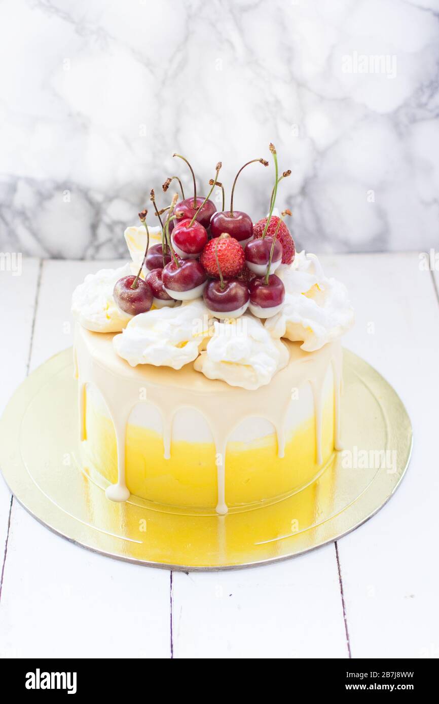 White and yellow colored cake with melted chocolate and fresh cherries ...