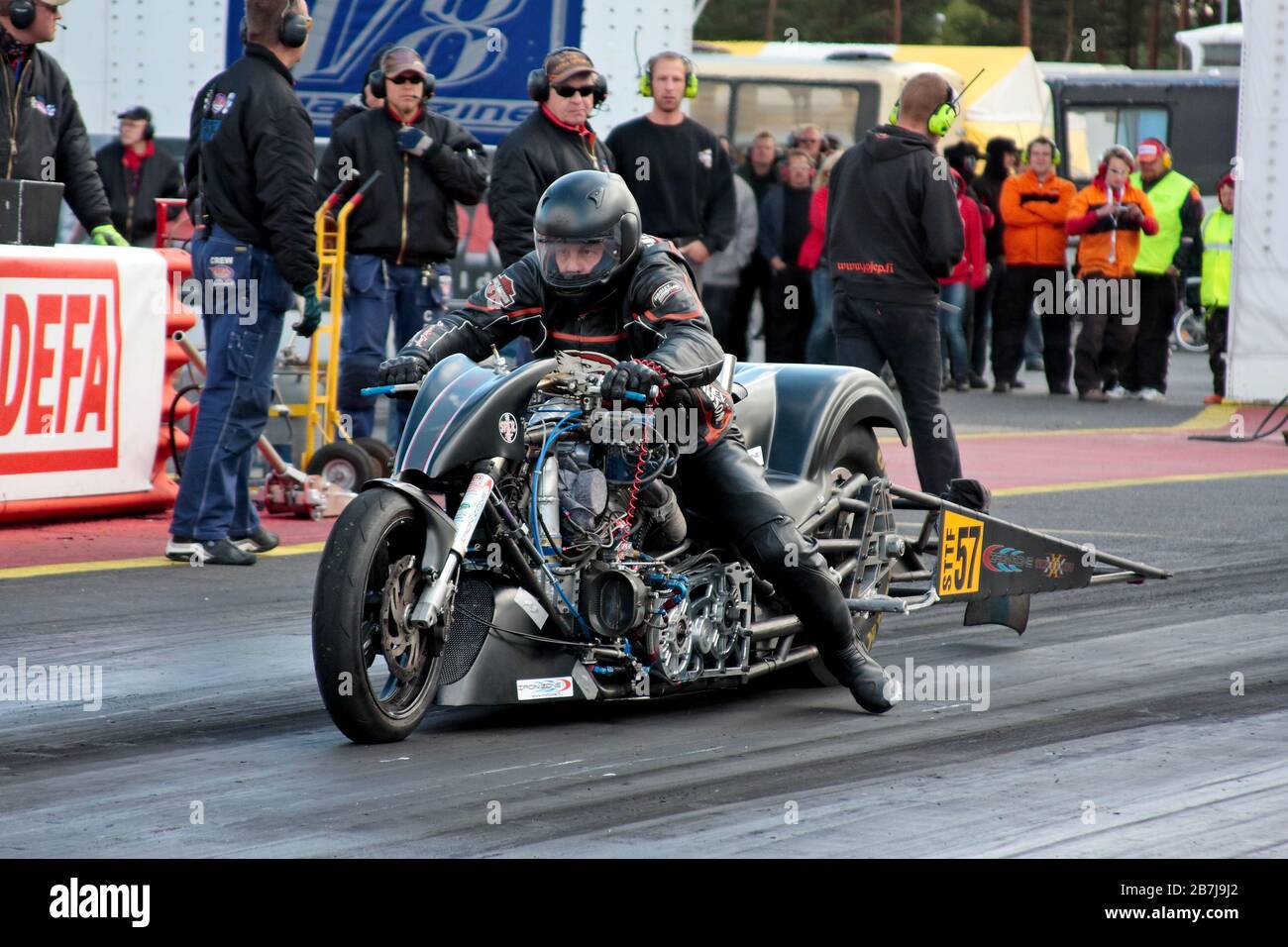 A drag race bike speeding up in quarter mile race with nitro burning ...