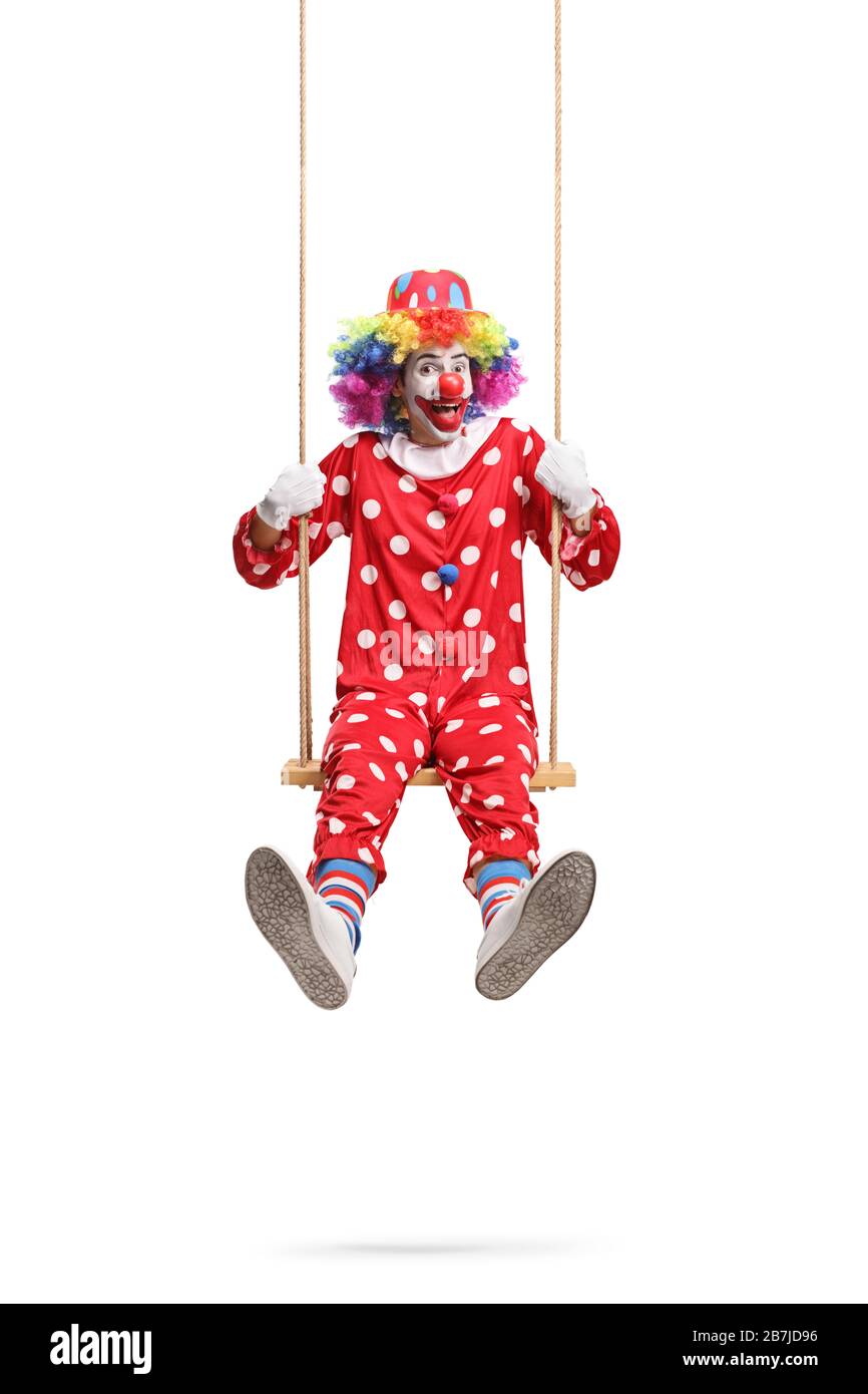 Cheerful funny clown playing on a wooden swing isolated on white ...
