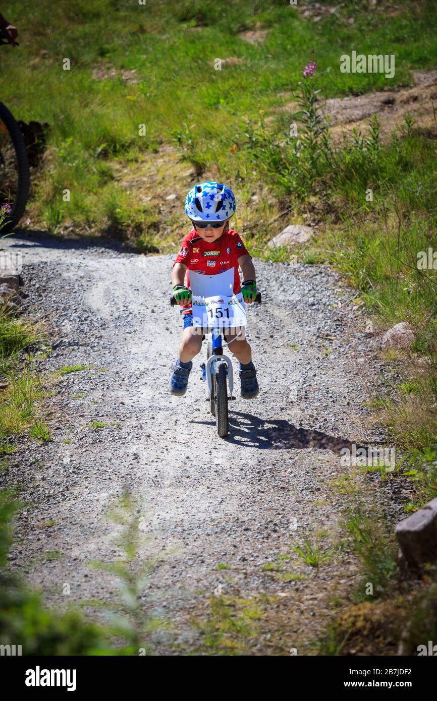 2-3 year old kid on kick-bike, with sunglasses and helmet, at a bike ...