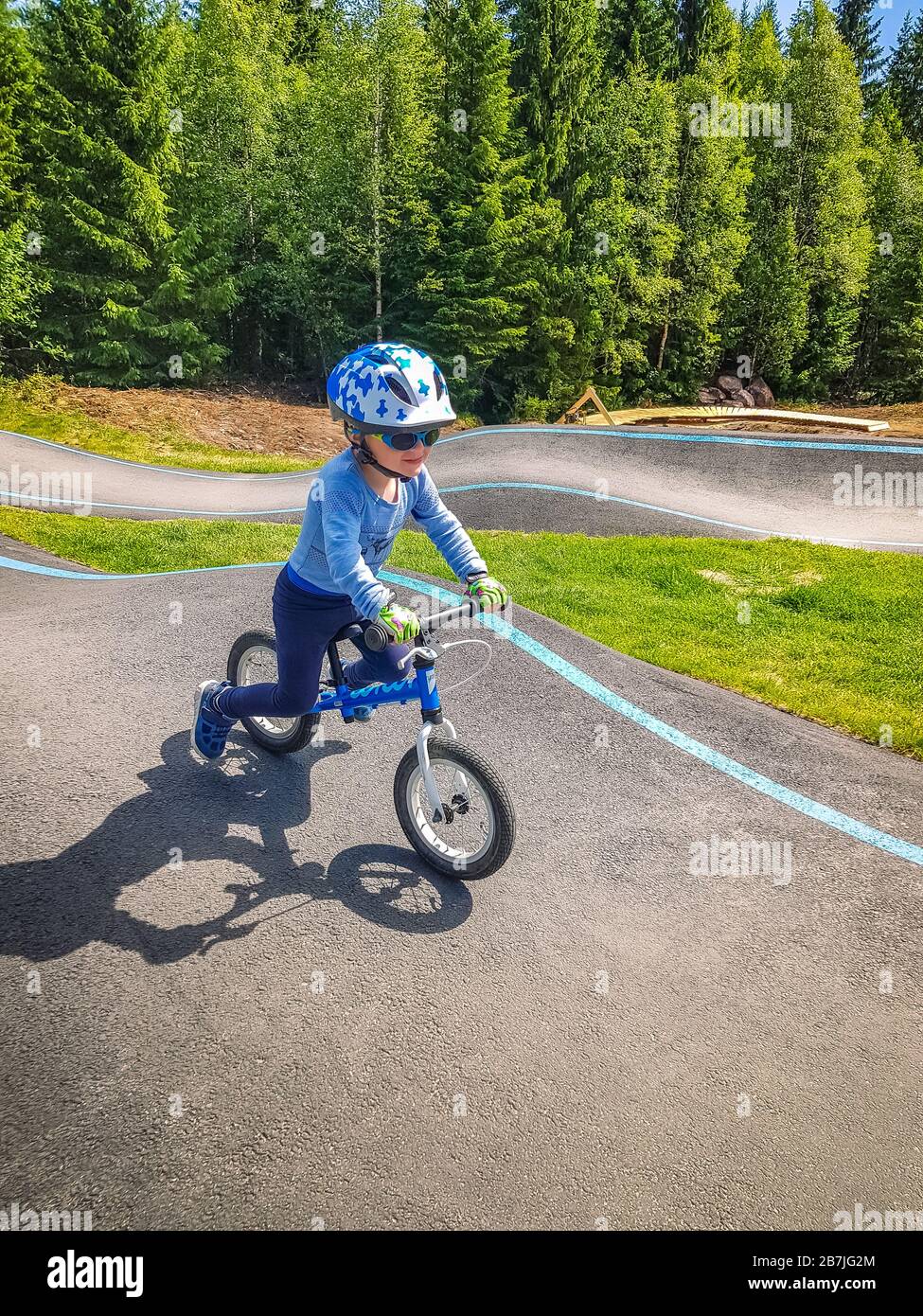 2-3 year old kid on kick-bike, with sunglasses and helmet, at a bike ...
