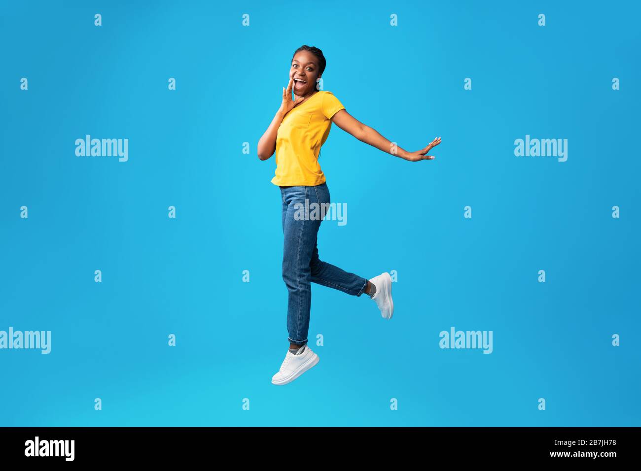 Cheerful Woman Shouting Jumping In Air On Blue Background Stock Photo ...
