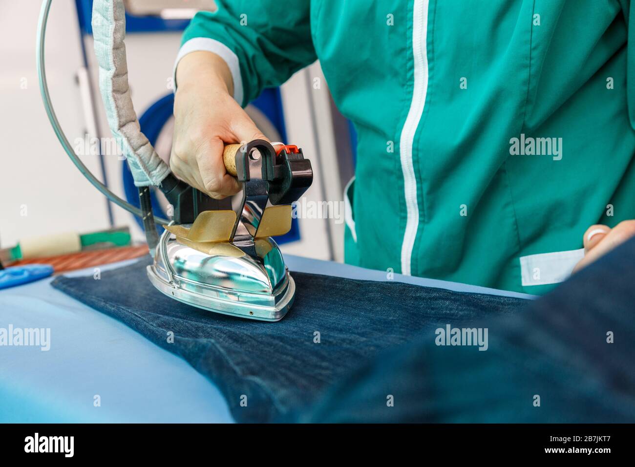 Female hand ironing blue jeans in a dry cleaning laundry service Stock ...