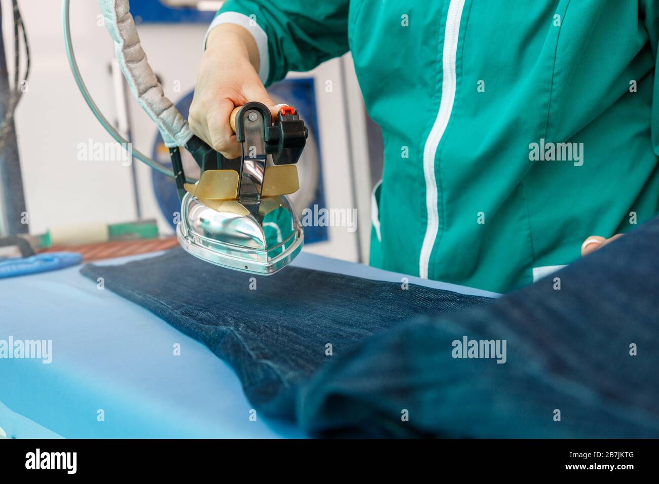 Female hand ironing blue jeans in a dry cleaning laundry service Stock ...