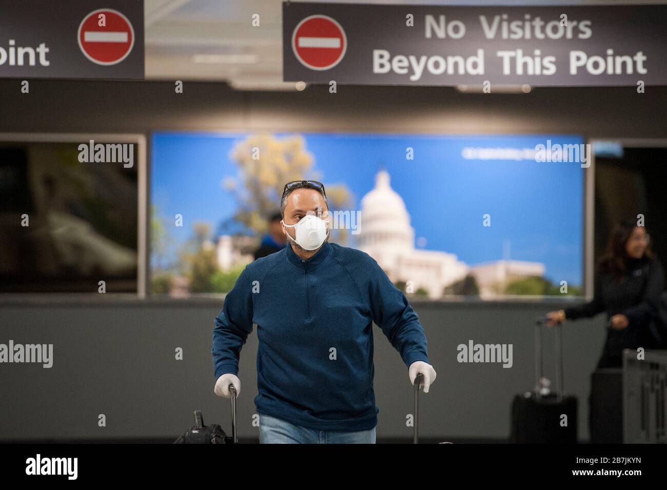 A man wears a protective mask as he and other passengers arrive from ...
