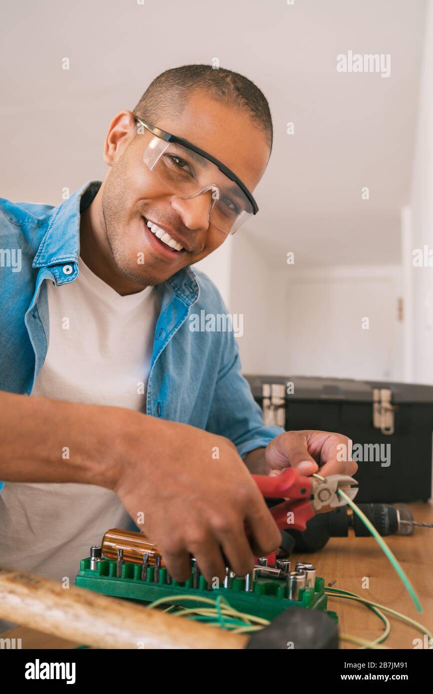 Portrait of young latin man fixing electricity problem with cables at ...