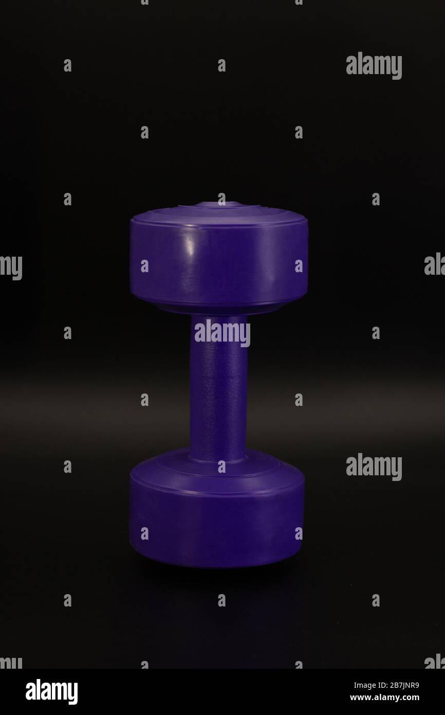 Purple dumbbell positioned vertically on a dark background. Wellness ...