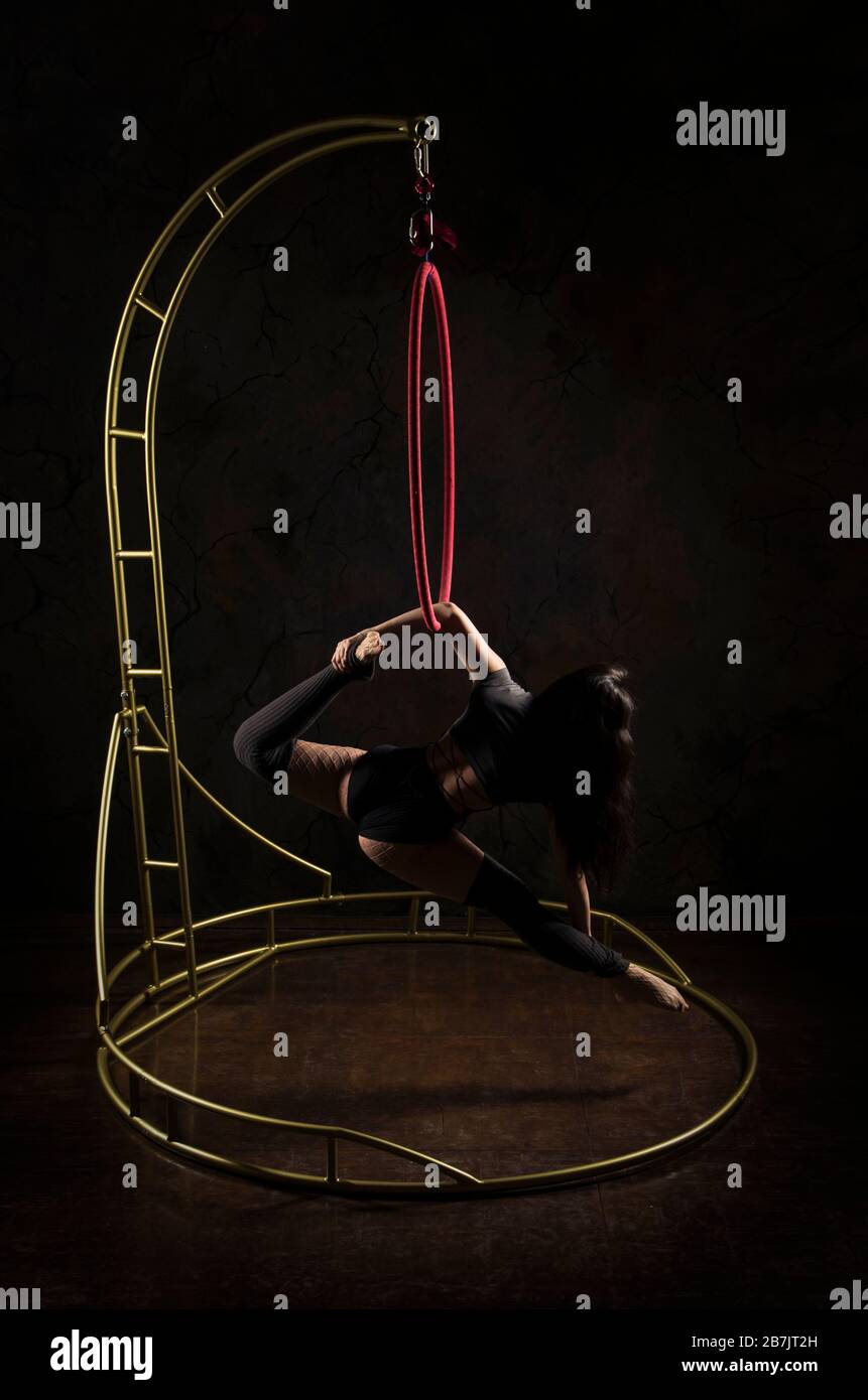 Gorgeous woman, aerial acrobat, in a dark suit performs acrobatic ...