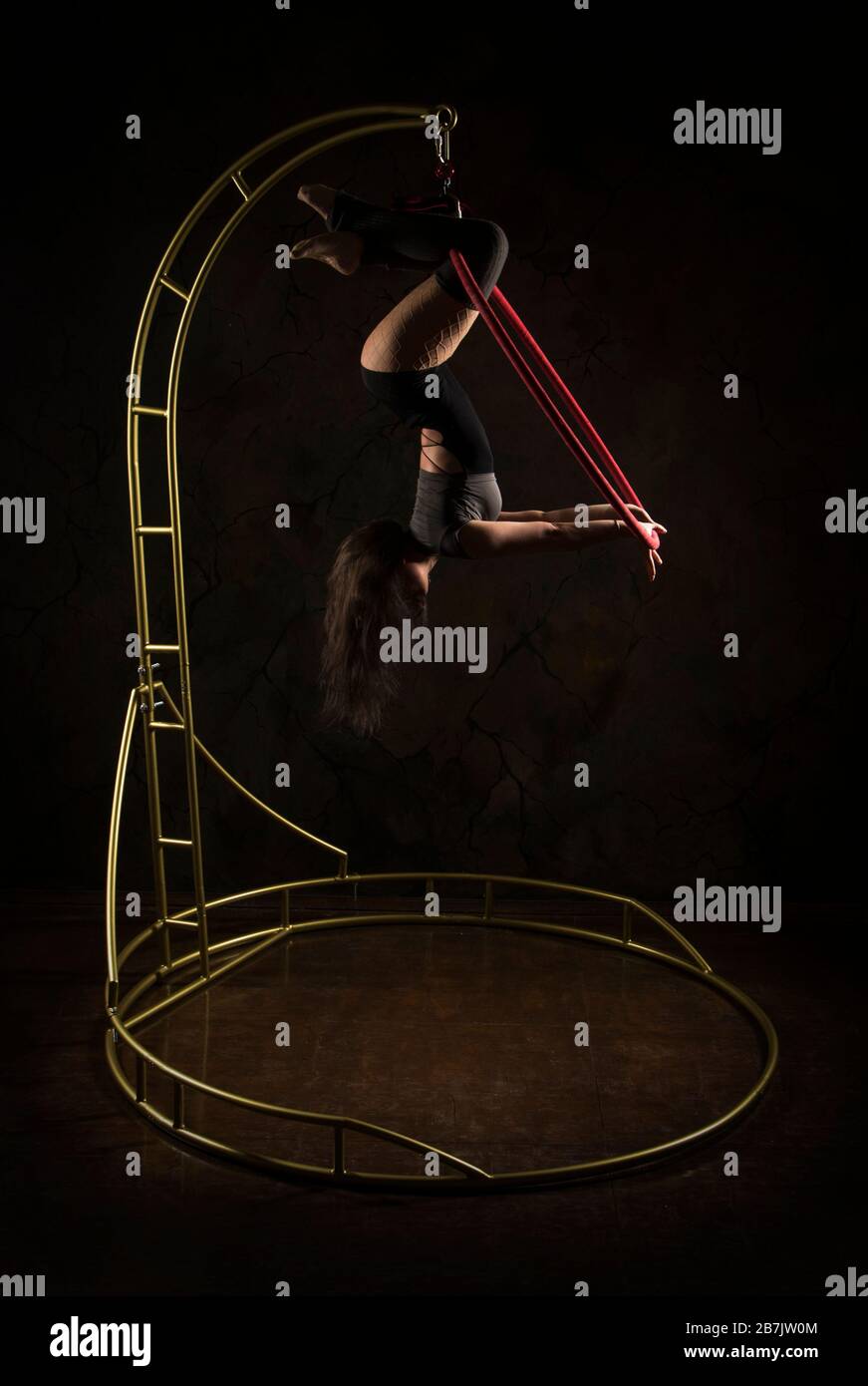 Gorgeous woman, aerial acrobat, in a dark suit performs acrobatic ...