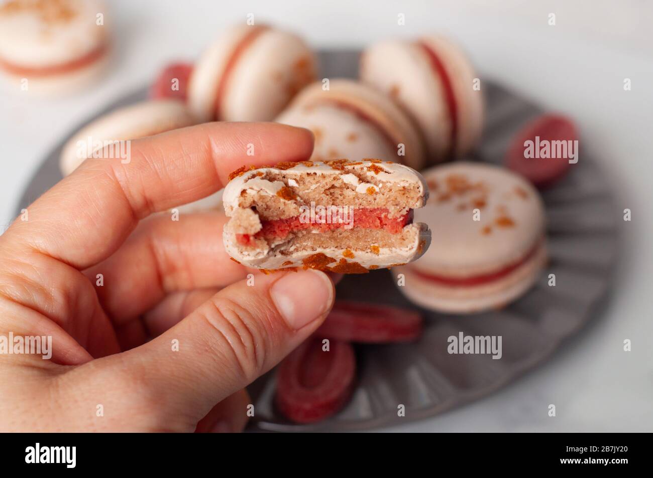 Hand holds a strawberry macaron Stock Photo - Alamy