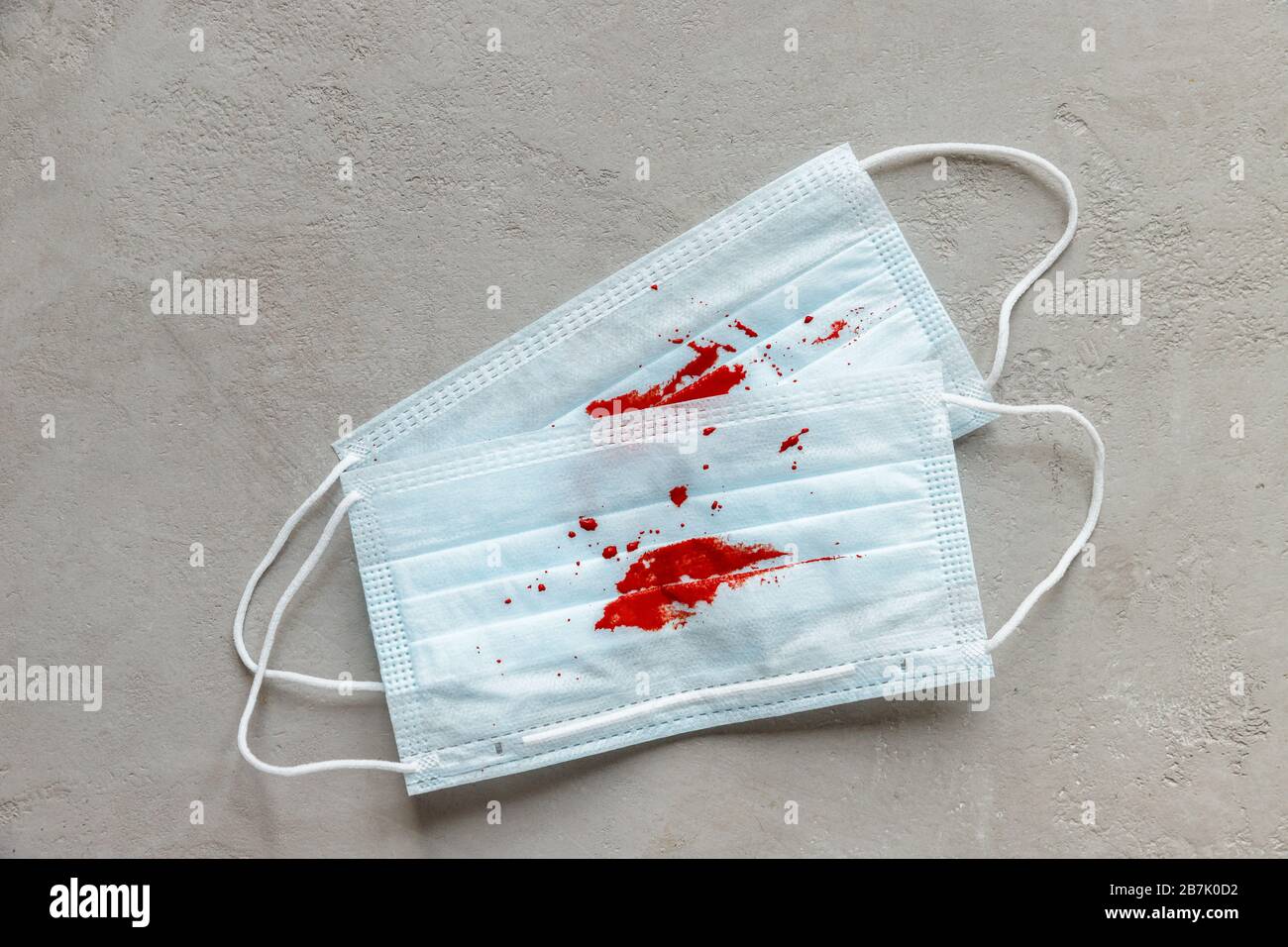 Two facial medical face mask with coughing blood, top view, concrete ...