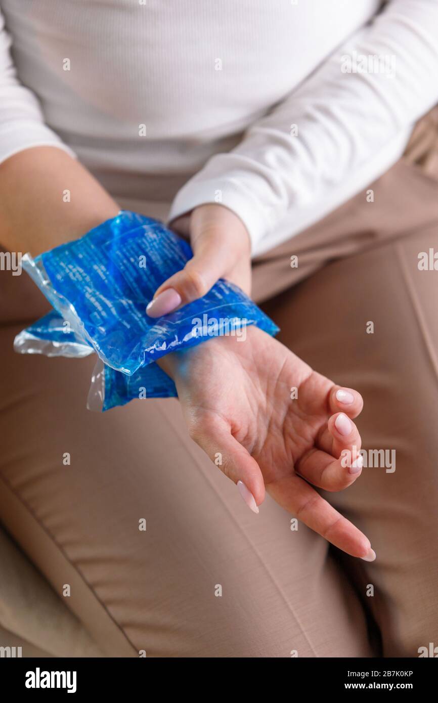 Close up of woman applying cold compress to a her painful wrist caused ...