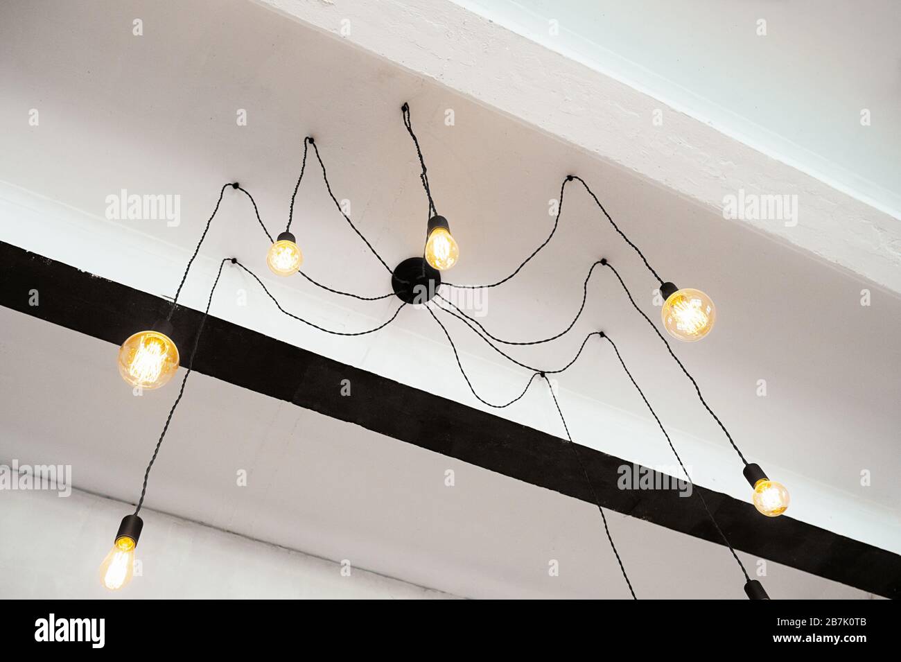 Unusual black loft chandelier on a white ceiling. The chandelier looks ...