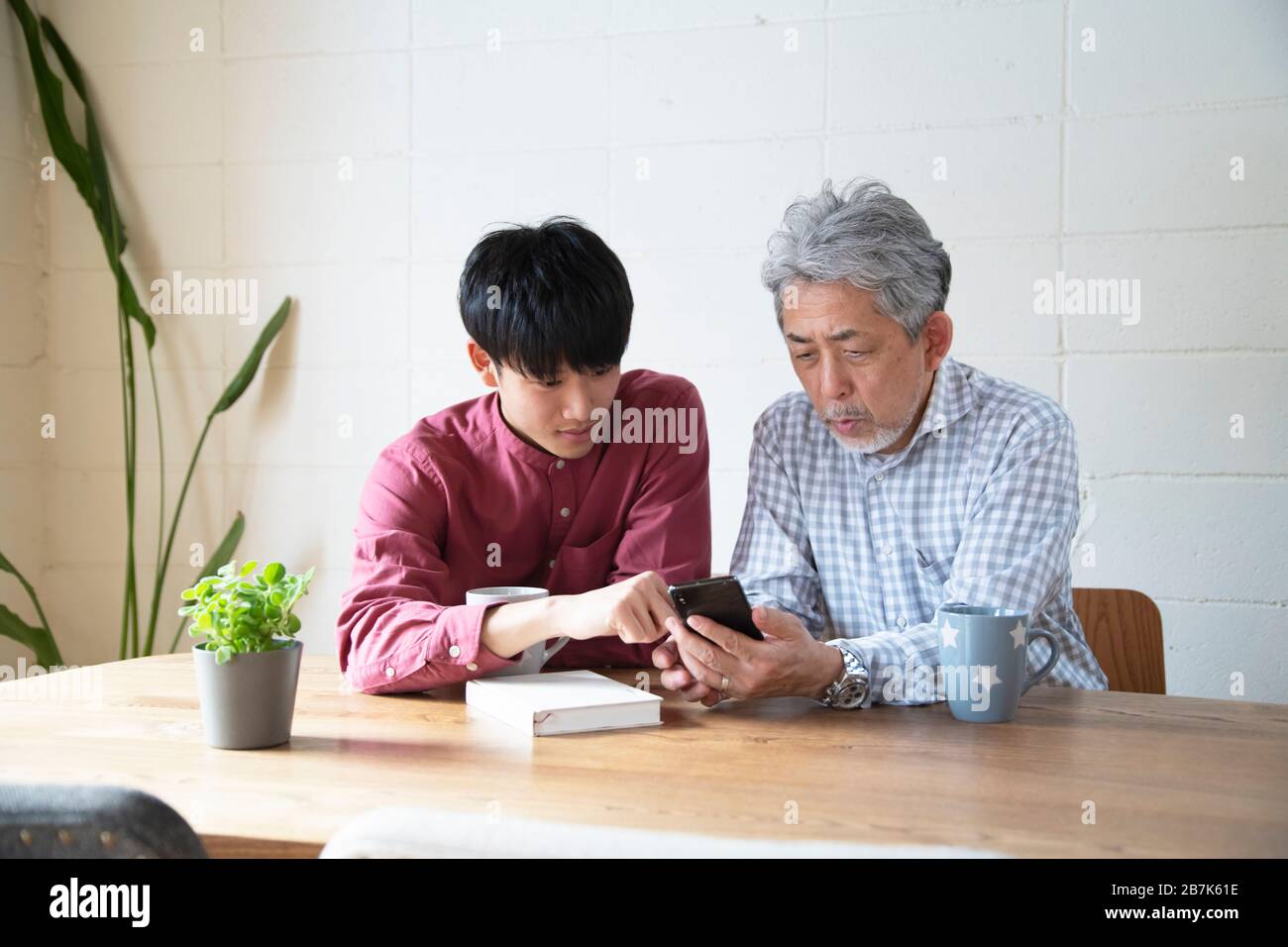 Senior instructed smartphone by young man Stock Photo - Alamy