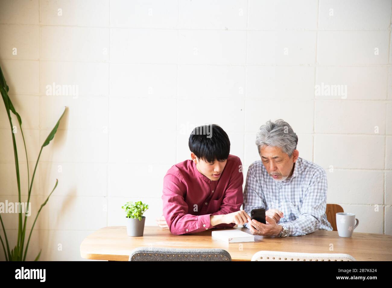 Senior instructed smartphone by young man Stock Photo - Alamy