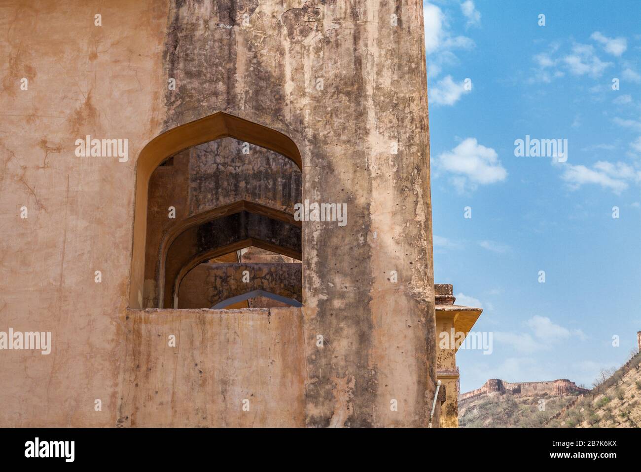 Arched windows in Amer Fort, with fortified wall in the background ...
