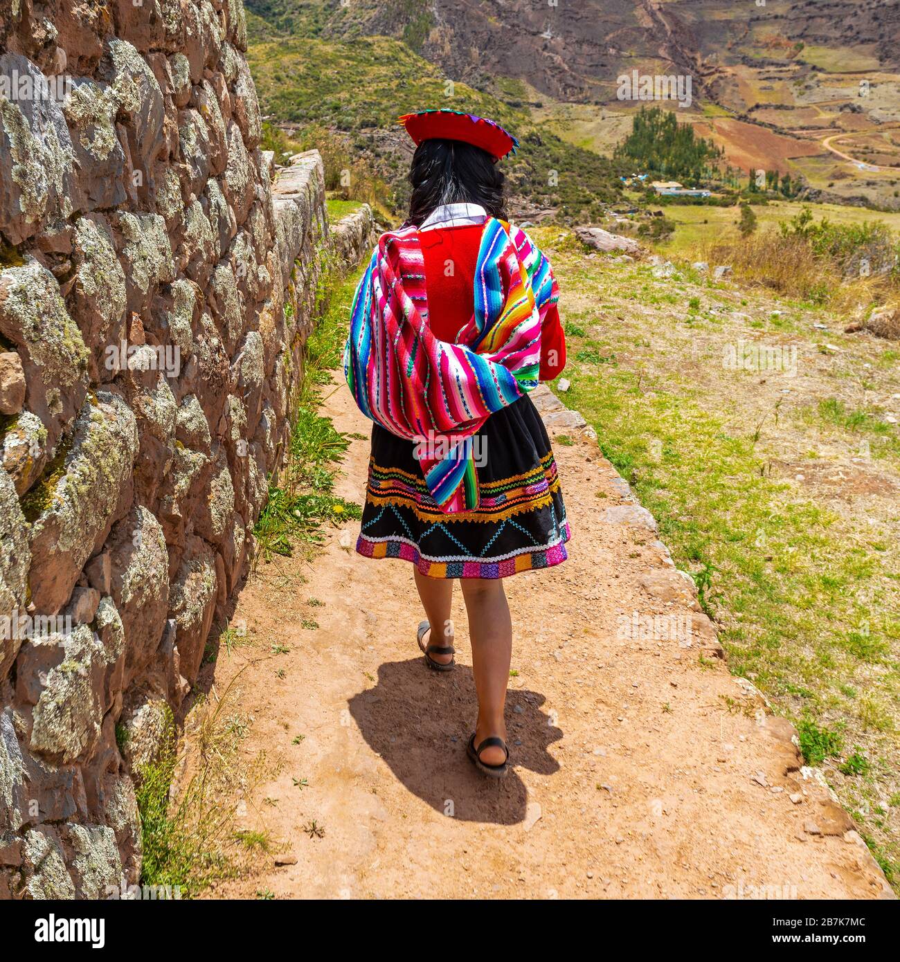 Indigenous Quechua woman with traditional clothing walking along an ...